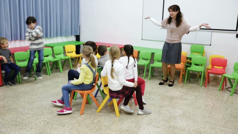 Happy Kids and Female Teacher Playing Musical Chairs Together during ... Happy Kids and Female Teacher Playing Musical Chairs Together during ...