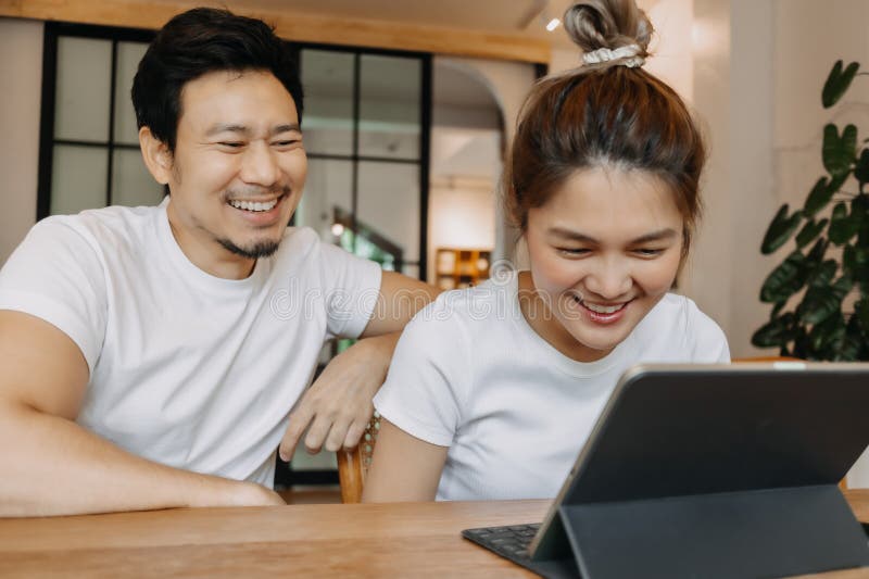 Happy Laughing Asian Couple Watching Computer Tablet Together in the ...