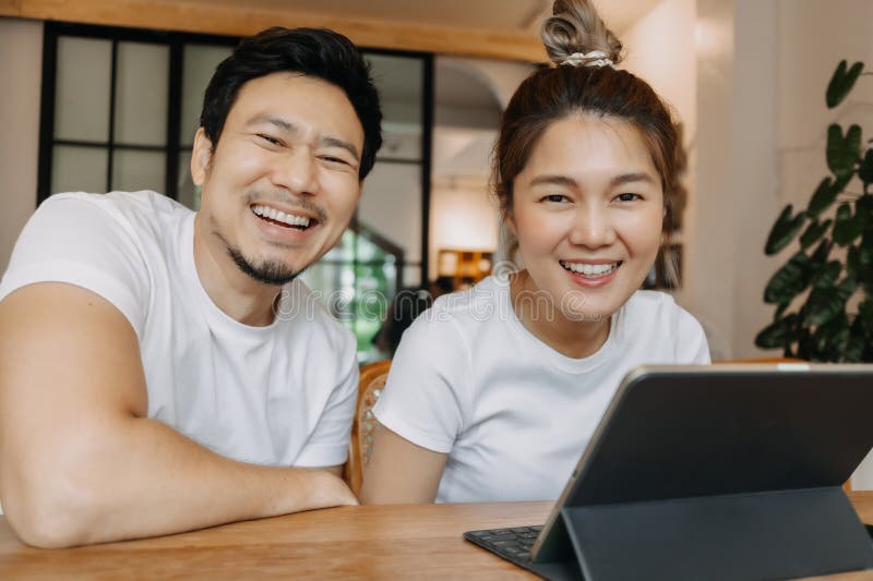 Happy Laughing Asian Couple Watching Computer Tablet Together in the ...