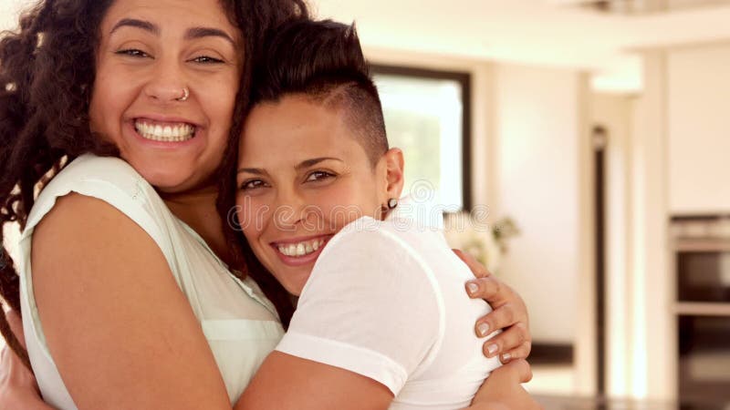 Happy Lesbian Couple Hugging And Holding Rainbow Flag In Park And