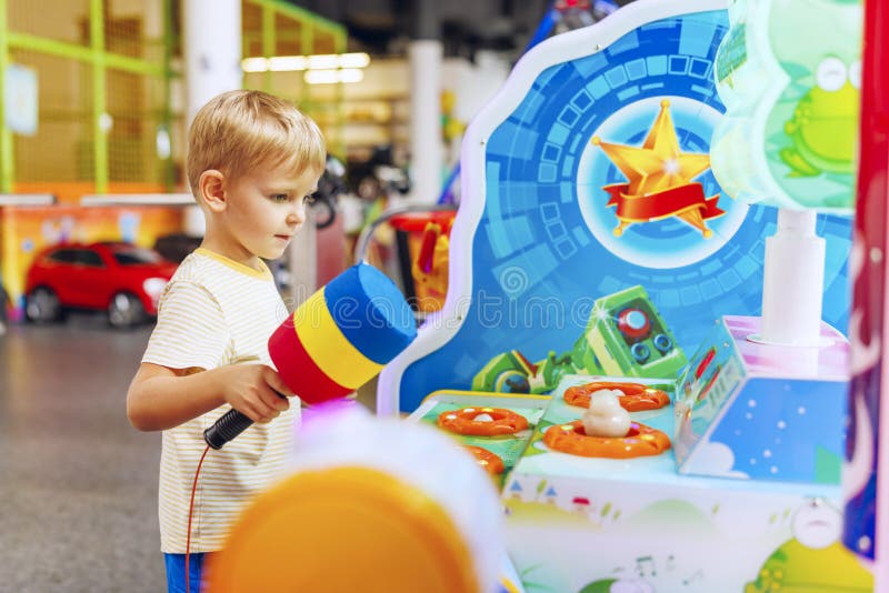 Happy Little Boy Playing Fun Games on Arcade Machine at an Amusement ...