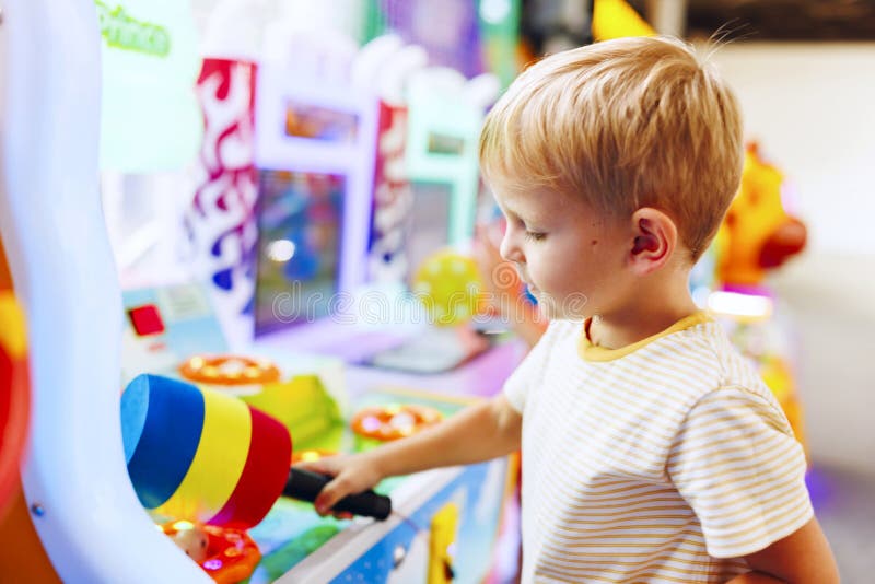 Happy Little Boy Playing Fun Games on Arcade Machine at an Amusement ...