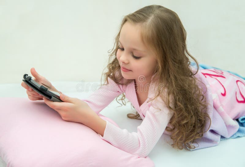 Happy Little Girl Lying on Bed with Tablet Computer Stock Image - Image ...