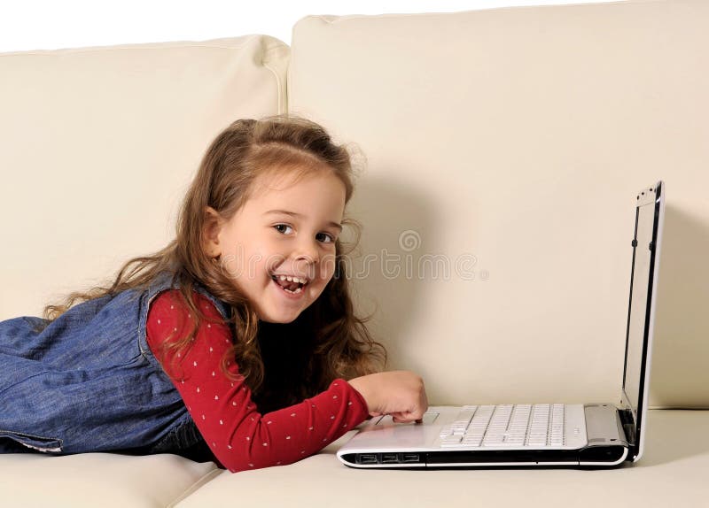 Happy Little Girl Lying on Couch Playing with Computer Stock Photo ...
