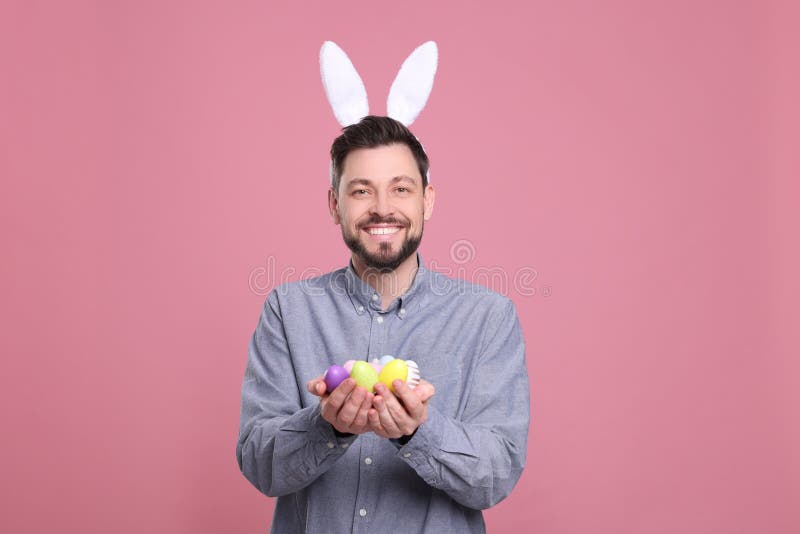 Happy Man in Bunny Ears Headband Holding Painted Easter Eggs on Pink ...