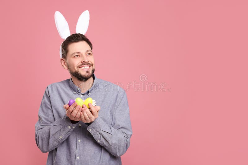 Happy Man in Bunny Ears Headband Holding Painted Easter Eggs on Pink ...