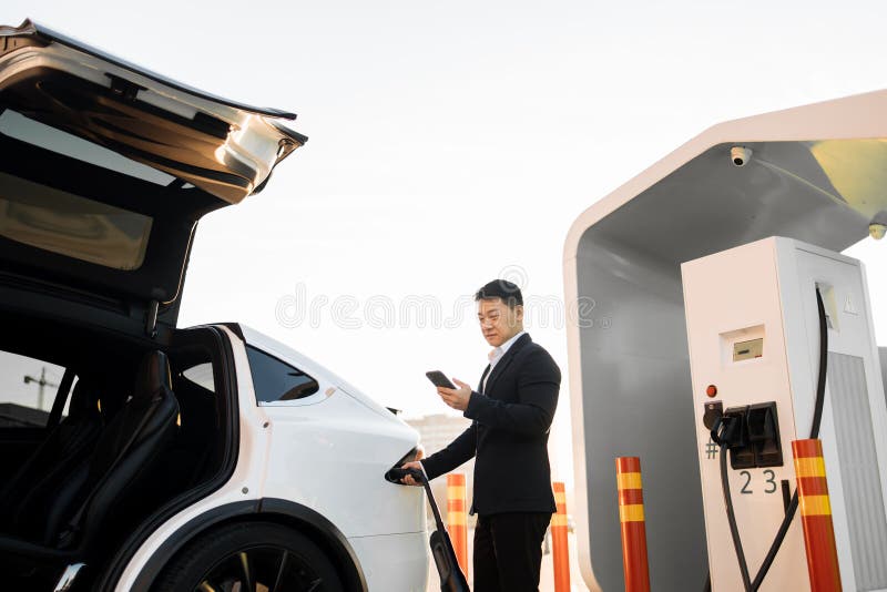 Happy Man Charging Electro Car and Using Smartphone Stock Photo - Image ...
