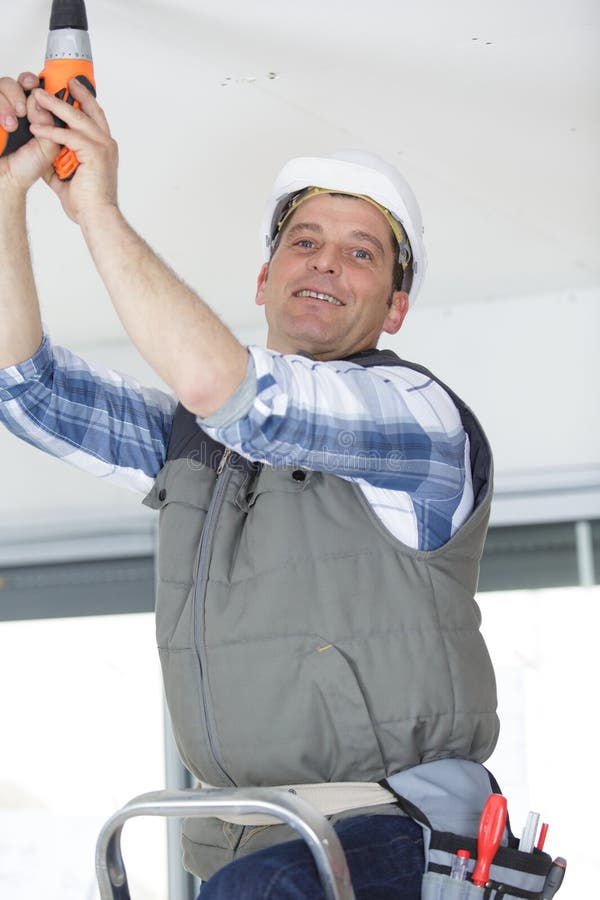 Happy man drilling ceiling stock image. Image of house - 331785123