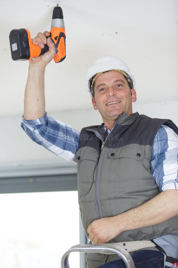 Happy man drilling ceiling stock image. Image of professional - 269813261