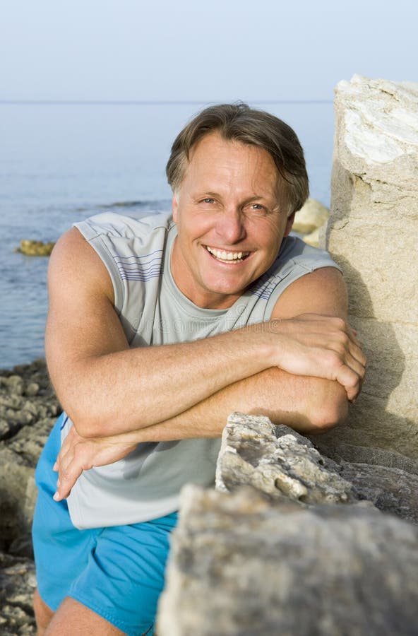 Happy Man Leaning on a Rock Stock Image - Image of copyspace, beach ...