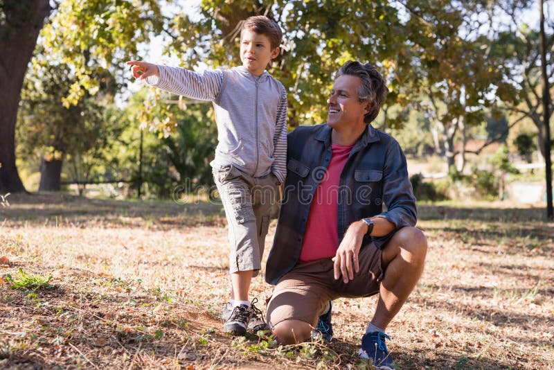 Happy Man Looking at Boy Pointing Away in Forest Stock Image - Image of ...