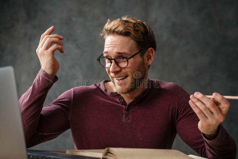 The Happy Man Looking into the Laptop Screen while Sitting at the Table ...