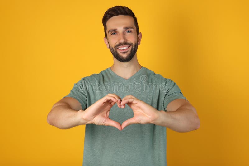 Happy Man Making Heart with Hands on Yellow Background Stock Photo ...