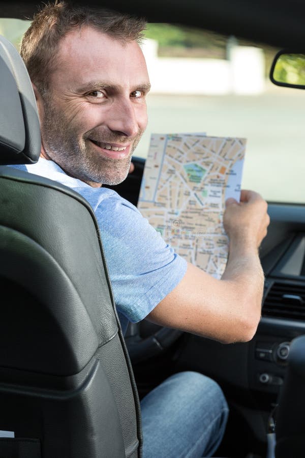 Happy man with map in car stock image. Image of assistance - 216071515