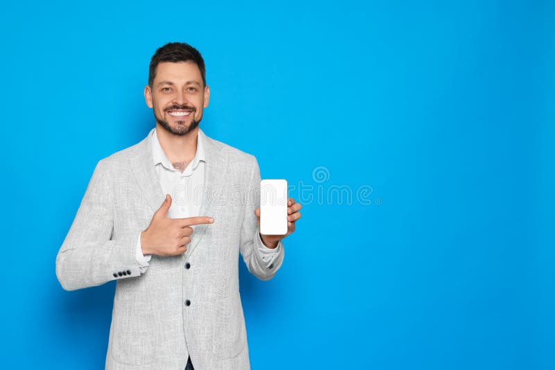 Happy Man Pointing At Smartphone On Light Blue Background Space For
