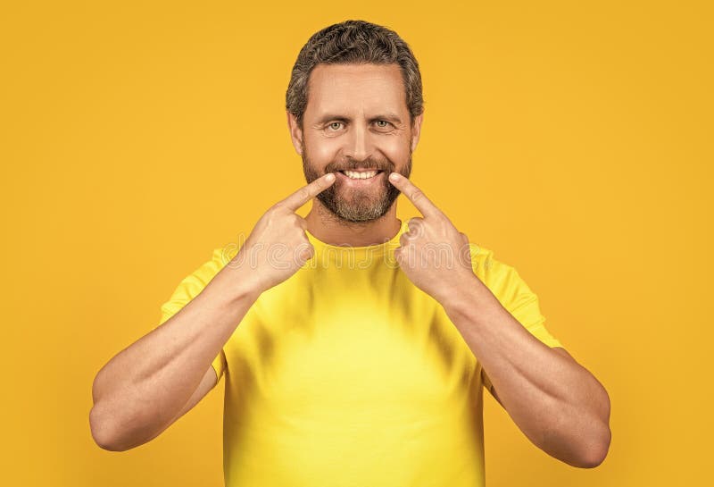 Happy Man Pointing at Teeth Smile Isolated on Yellow. Man Pointing at ...