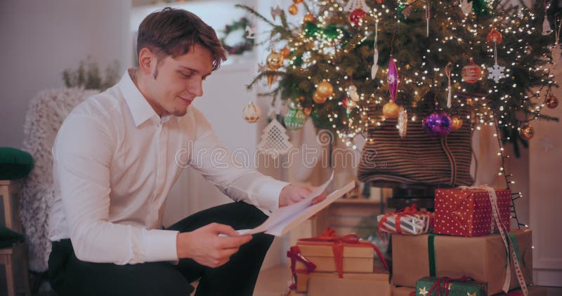 Happy Man Reading Letter by Christmas Presents and Decorated Tree Stock ... Happy Man Reading Letter by Christmas Presents and Decorated Tree Stock ...