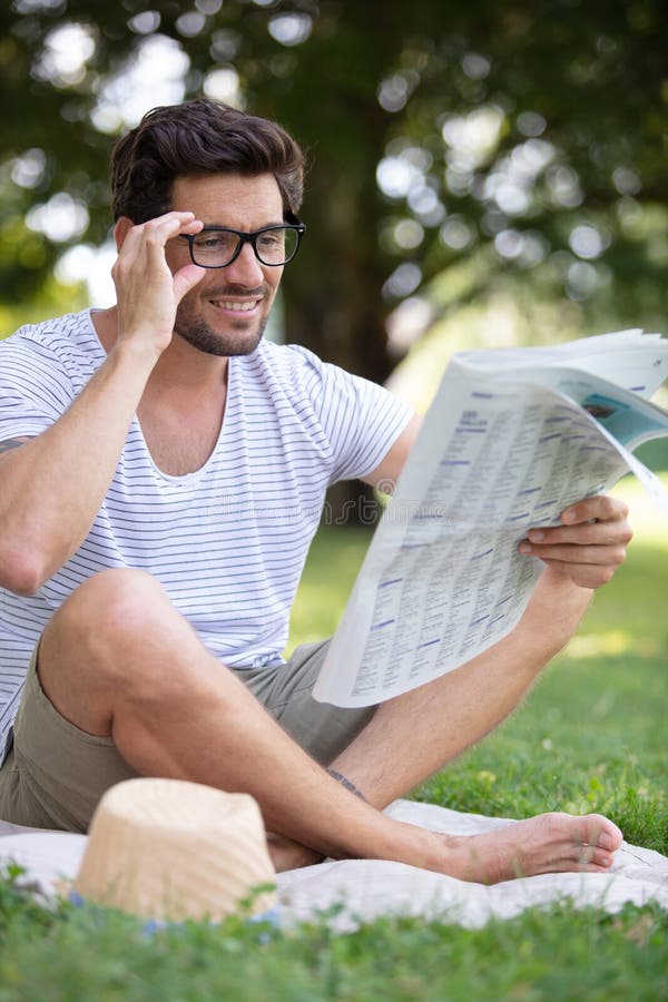 Happy Man Reading Newspaper on Grass Stock Photo - Image of young ...