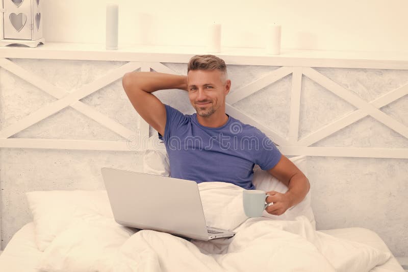 Happy Man Relax Drinking Coffee and Using Laptop Computer in Bed in ...
