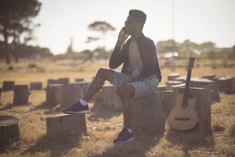 Happy Man Talking on Mobile Phone while Sitting on Tree Stump Stock ...