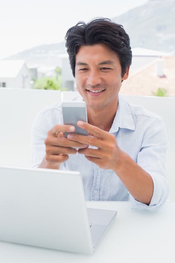 Happy Man Using His Laptop and Texting on Phone Stock Photo - Image of ...