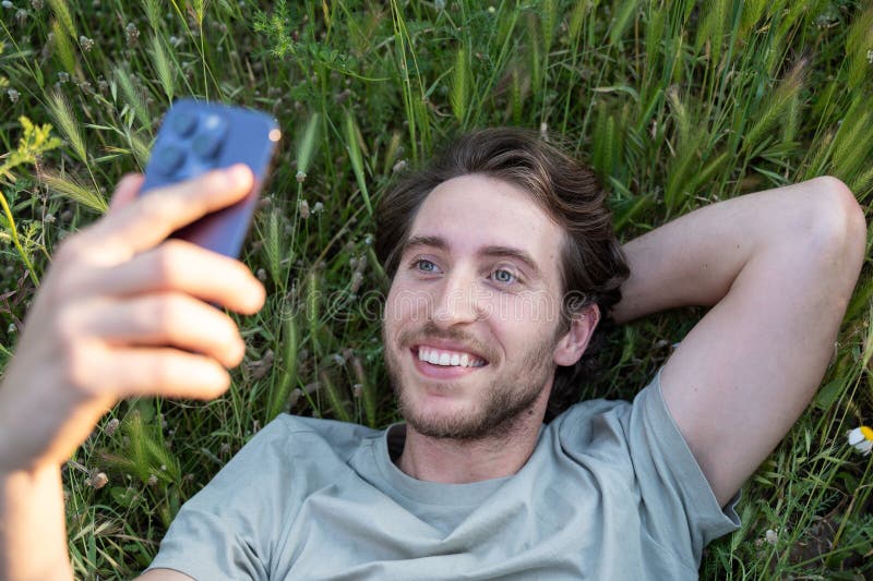 Happy Man Using His Mobile Phone Relaxing in the Green Grass in Summer ...