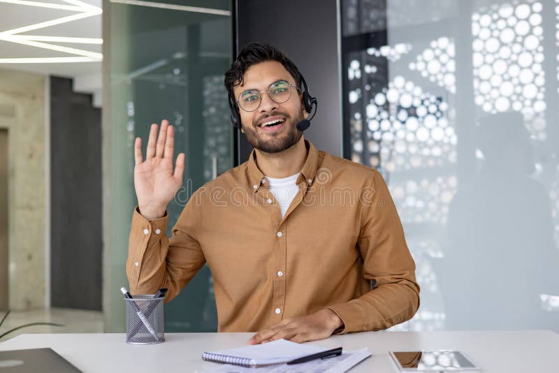 Happy Man Waving during a Video Chat Call in a Modern Office Stock ...