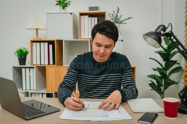 Happy Man Writing Document or Paperwork with Laptop at Home Office ...