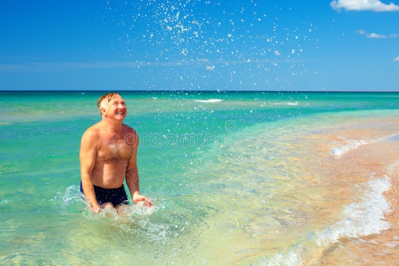 Happy Mature Man Splashing Water on the Beach Stock Photo - Image of ...
