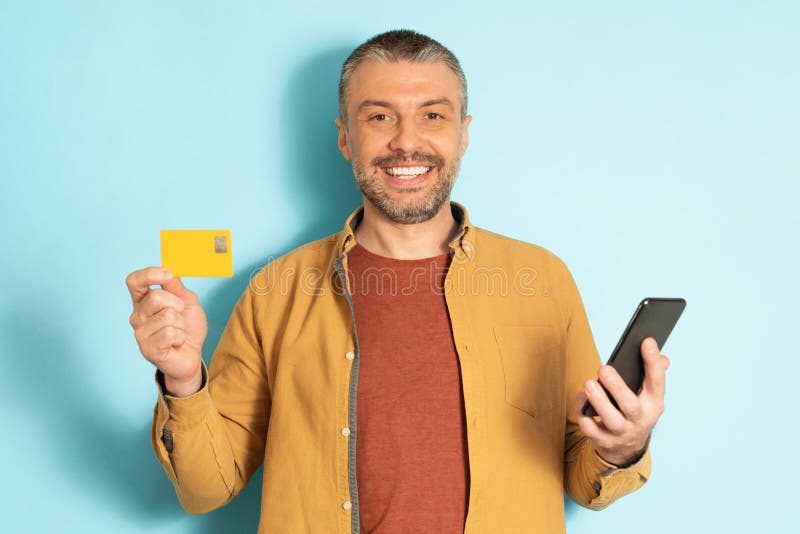 Happy Middle Aged Man Holding Credit Card and Using Cellphone for ... Happy Middle Aged Man Holding Credit Card and Using Cellphone for ...