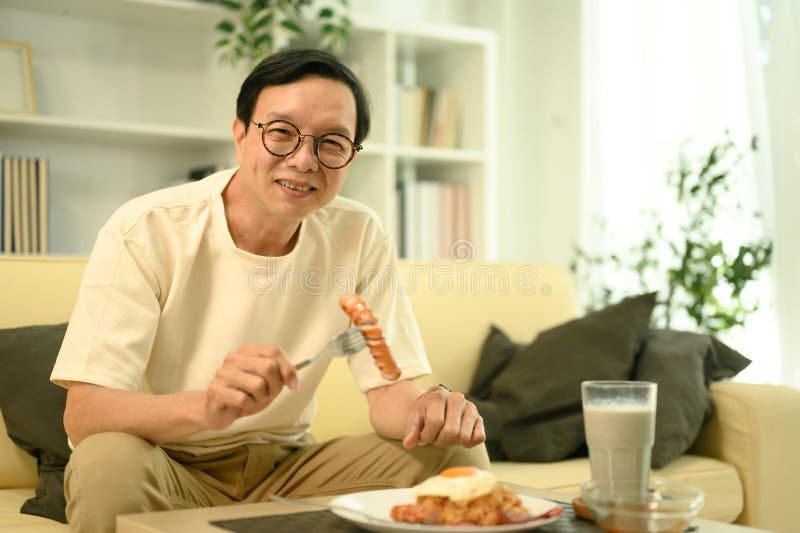 Happy Middle Aged Man Sitting on Sofa, Enjoying a Plate of Fried Rice ...