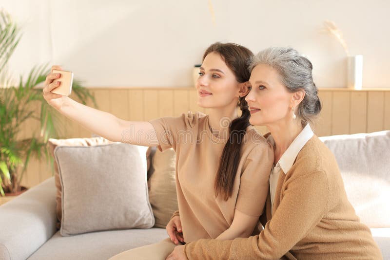 Happy Middle Aged Mother And Daughter Talking On Sofa In Living Room