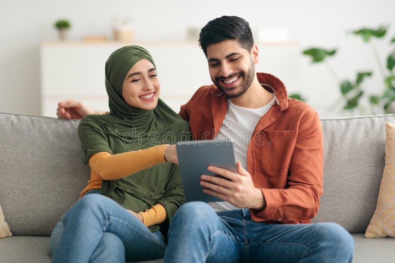 Happy Middle Eastern Spouses Using Digital Tablet Sitting at Home Stock ...