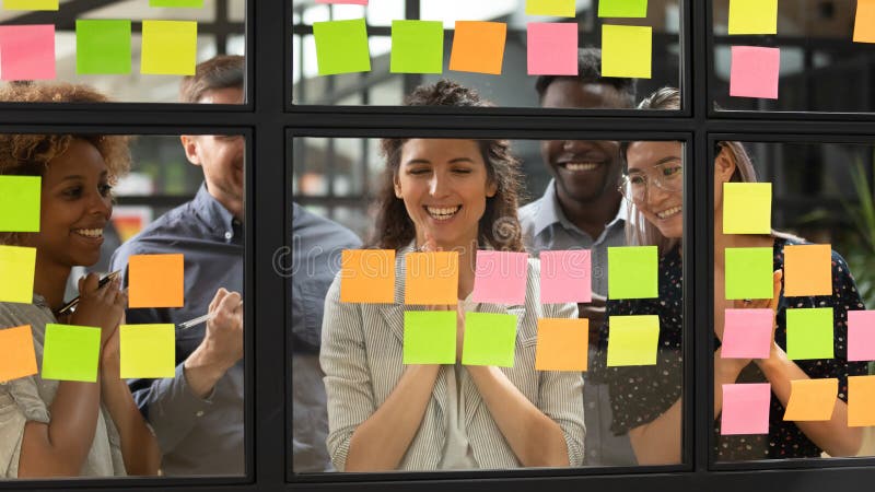 Happy Mixed Race Group Looking at Notes on Glass Board. Stock Image ...