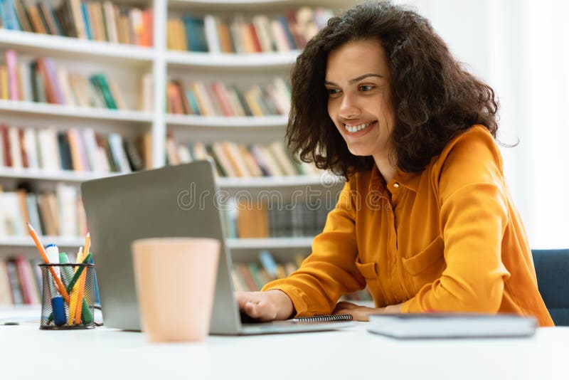 Happy Mixed Race Lady Sitting at Desk, Using Laptop and Watching ...
