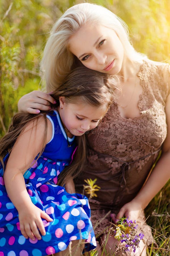 Happy Mom and Daughter Cuddle and Sit on the Grass Stock Image - Image ...
