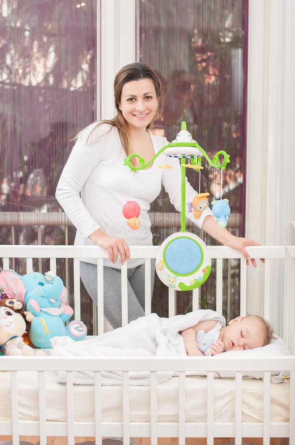 Happy Mother Standing beside the Baby`s Bed. Stock Photo - Image of ...