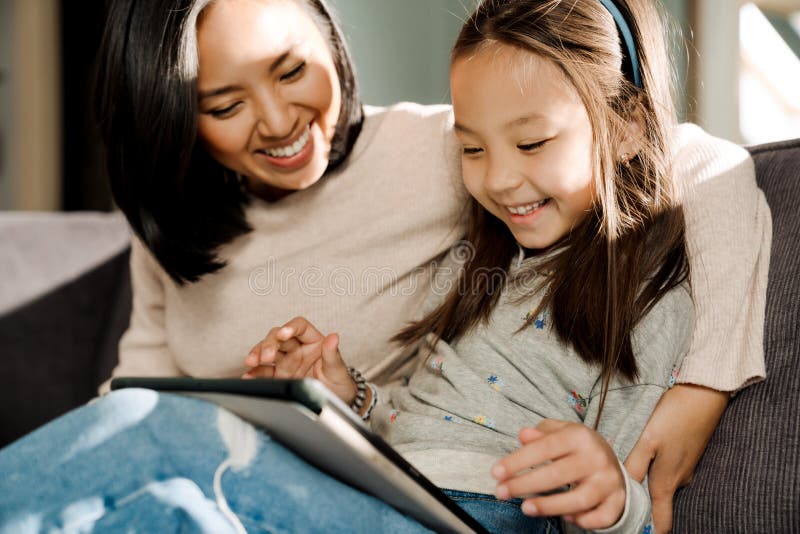 Happy Mother Using Tablet Computer while Hugging Her Daughter Stock ...