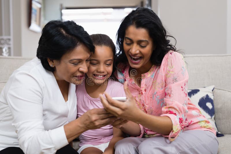 Happy Multi-generation Family Using Mobile Phone while Sitting Together ...