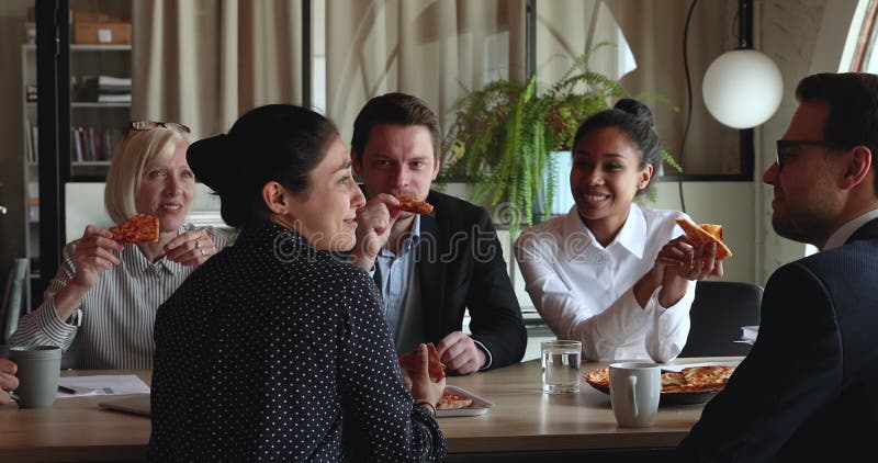 Happy Multiracial Diverse Colleagues Eating Pizza In Office Stock