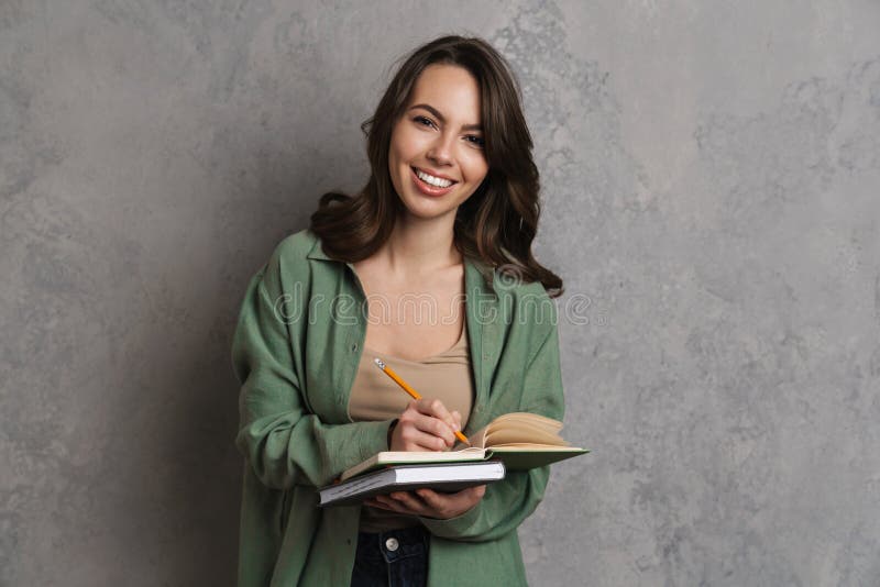 Happy Nice Girl Smiling and Writing Down Notes in Exercise Book Stock ...