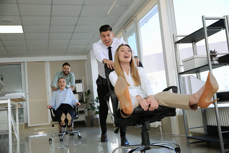 Happy Office Employees Riding Chairs at Workplace Stock Photo - Image ...