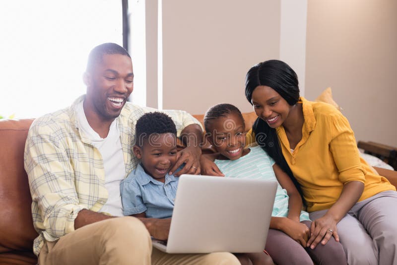 Happy Parents and Children Using Laptop while Sitting on Sofa Stock ...