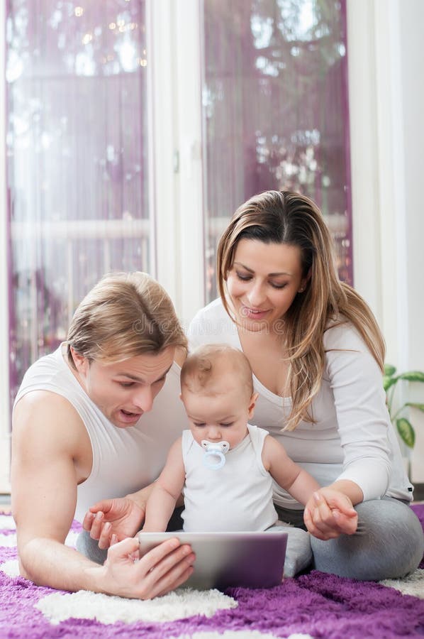 Happy Parents Laying Down on the Floor and Playing on Tablet with Their ...