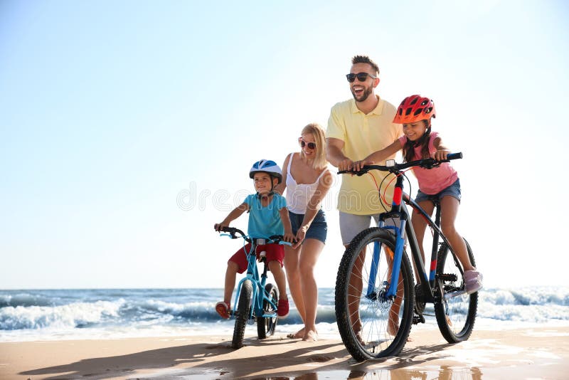 Happy Parents Teaching Children To Ride Bicycles on Beach Near Sea ... Happy Parents Teaching Children To Ride Bicycles on Beach Near Sea ...