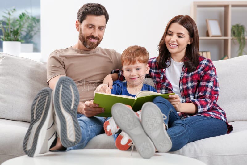 Happy Parents with Their Child Reading Book on Couch at Home Stock ...