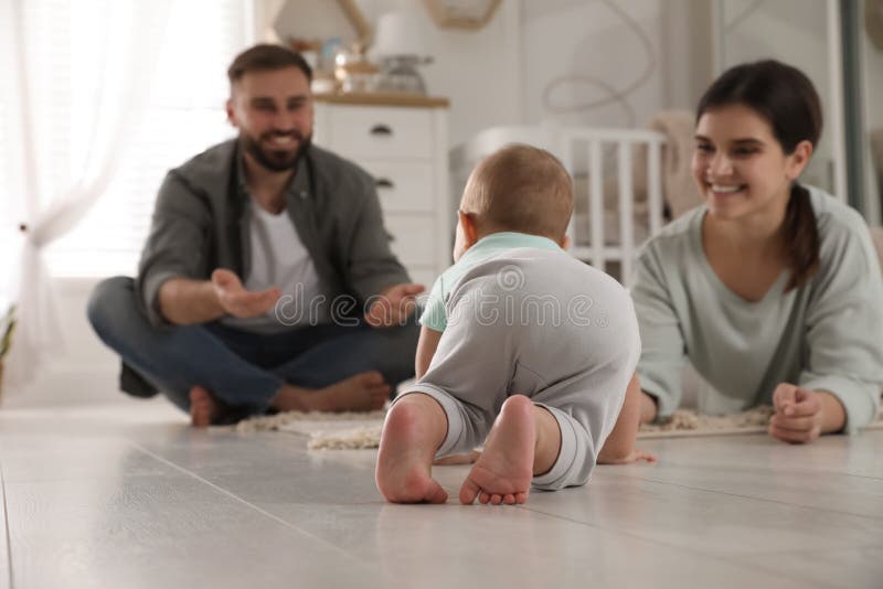 Happy Parents Watching Their Baby Crawl on Floor at Home Stock Photo ...