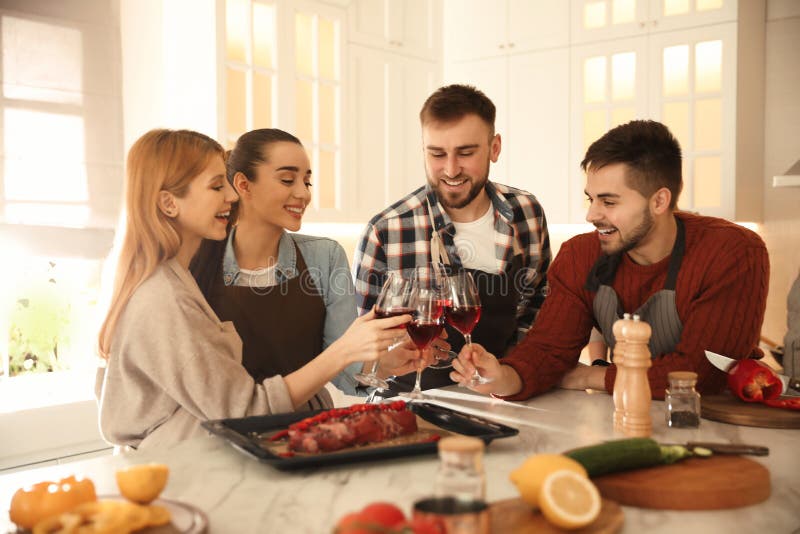Happy People Drinking Wine while Cooking Food in Kitchen Stock Photo ...