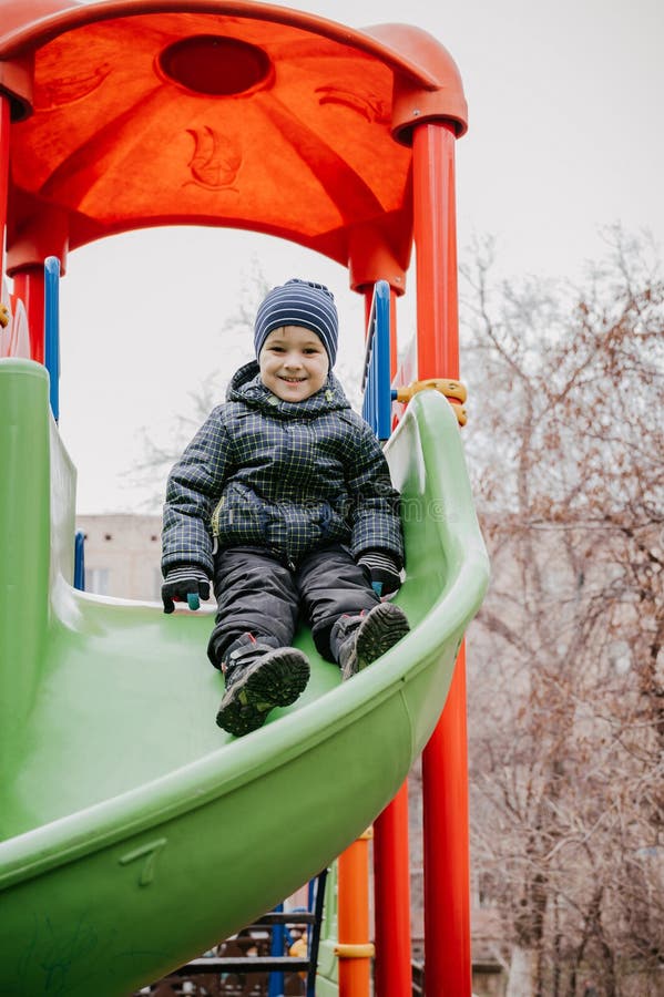 A Happy Preschooler Boy is Playing on a Slide in the Playground Stock ...