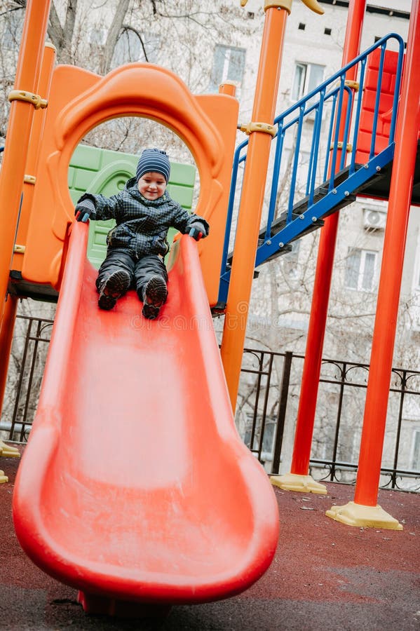 A Happy Preschooler Boy is Playing on a Slide in the Playground Stock ...